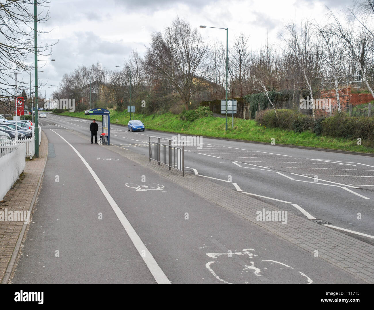 A lone man waits for a bus at a bus stop on a quiet street Stock Photo ...