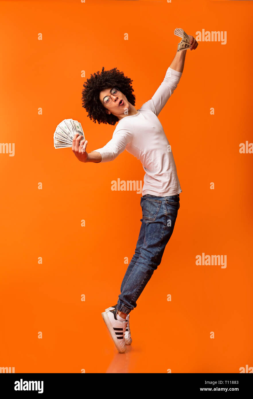 Young excited black man dancing with dollars Stock Photo - Alamy