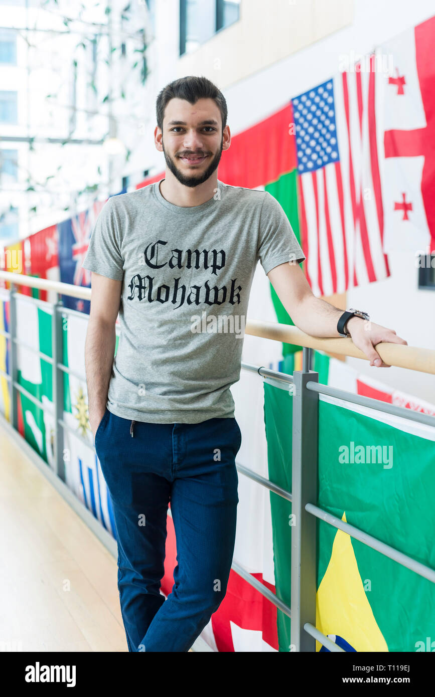 a male student stands in front of lots of international flags Stock ...