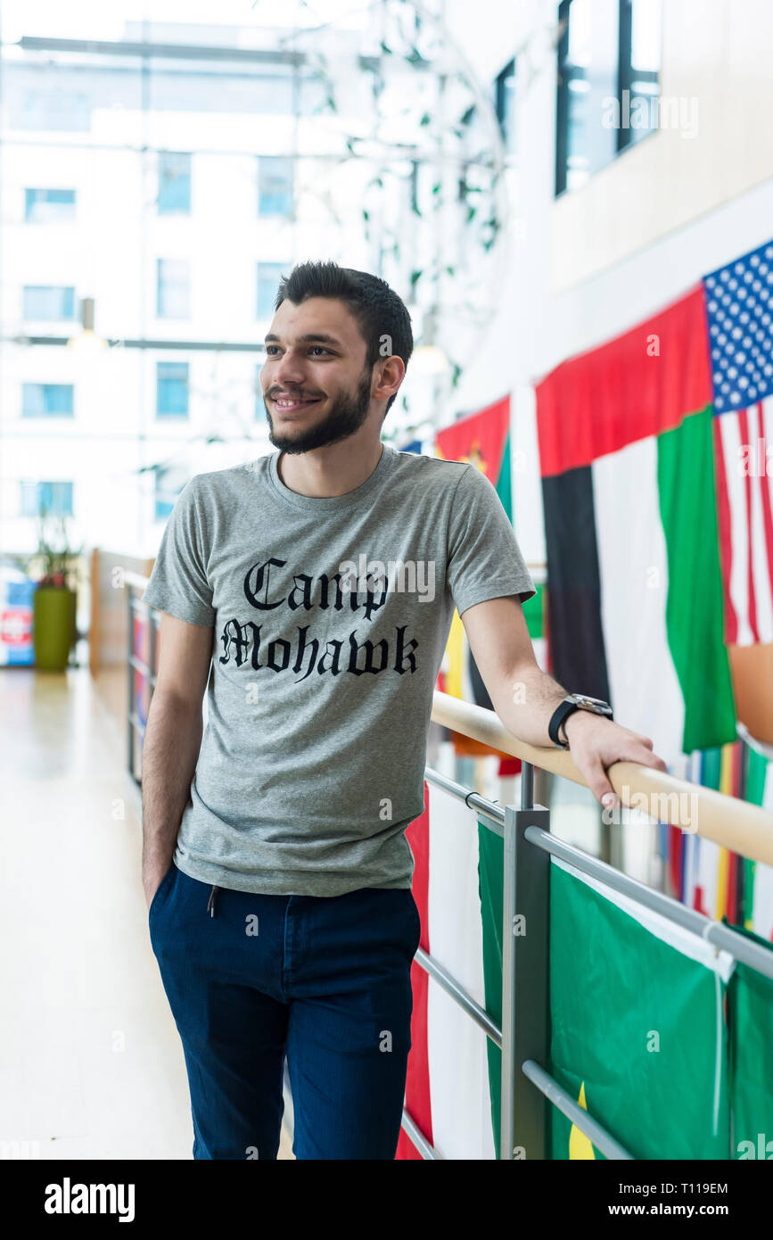a male student stands in front of lots of international flags Stock ...