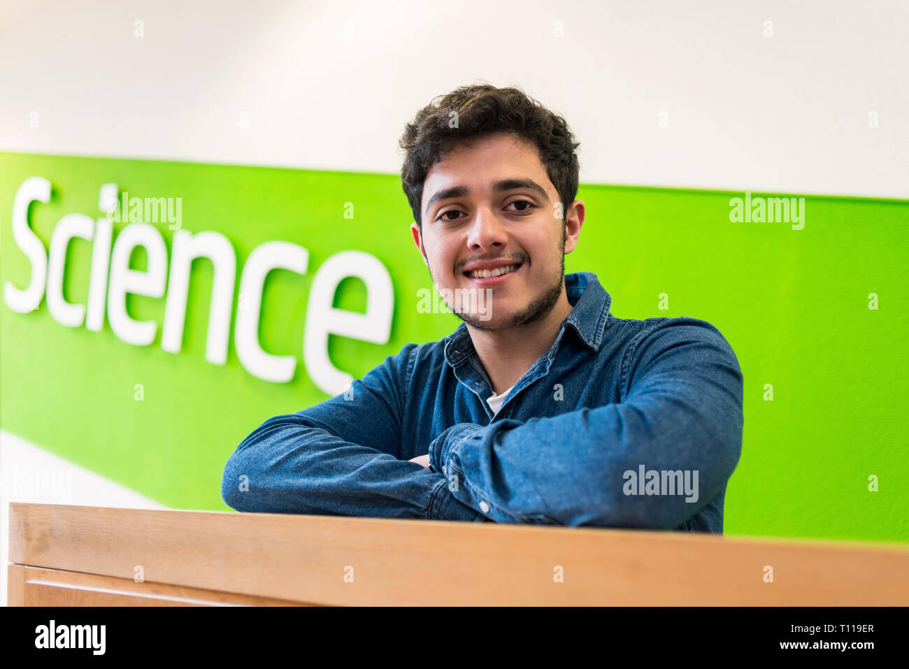 a male student stands in front of a big sign which says science Stock ...