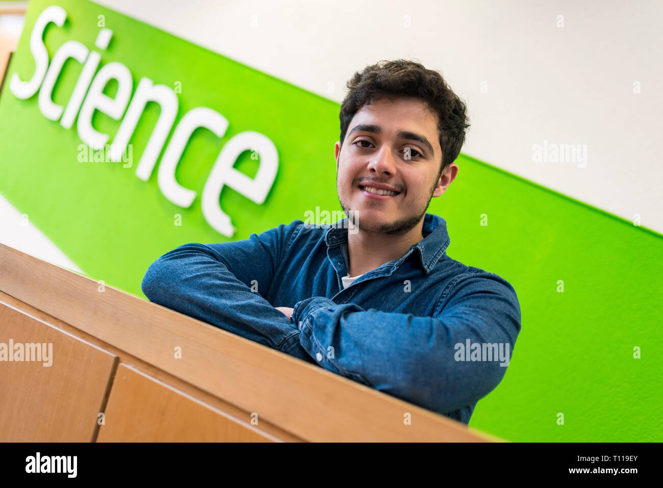 a male student stands in front of a big sign which says science Stock ...