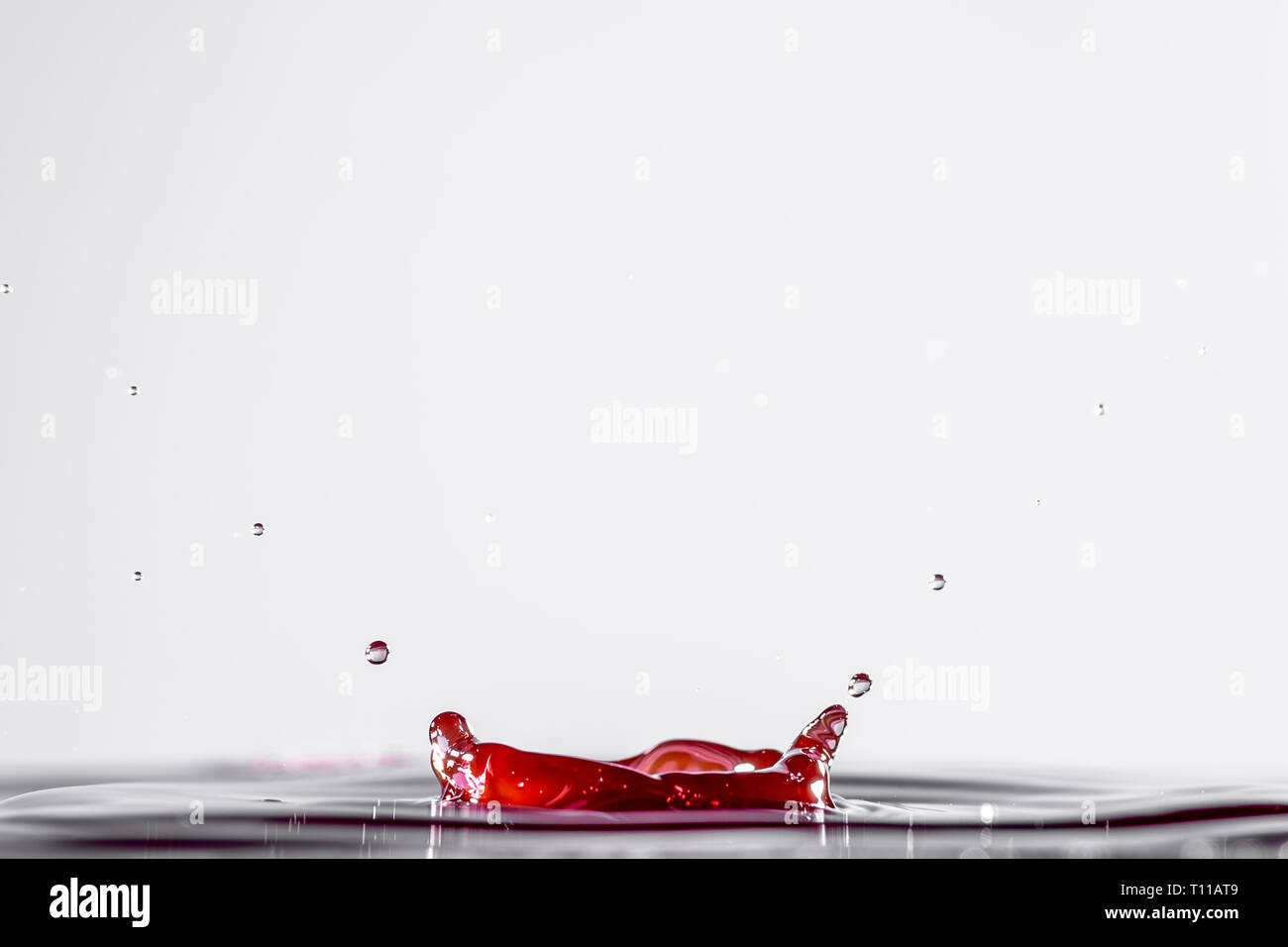 Vibrant red water droplets and ripples isolated on a clean background ...
