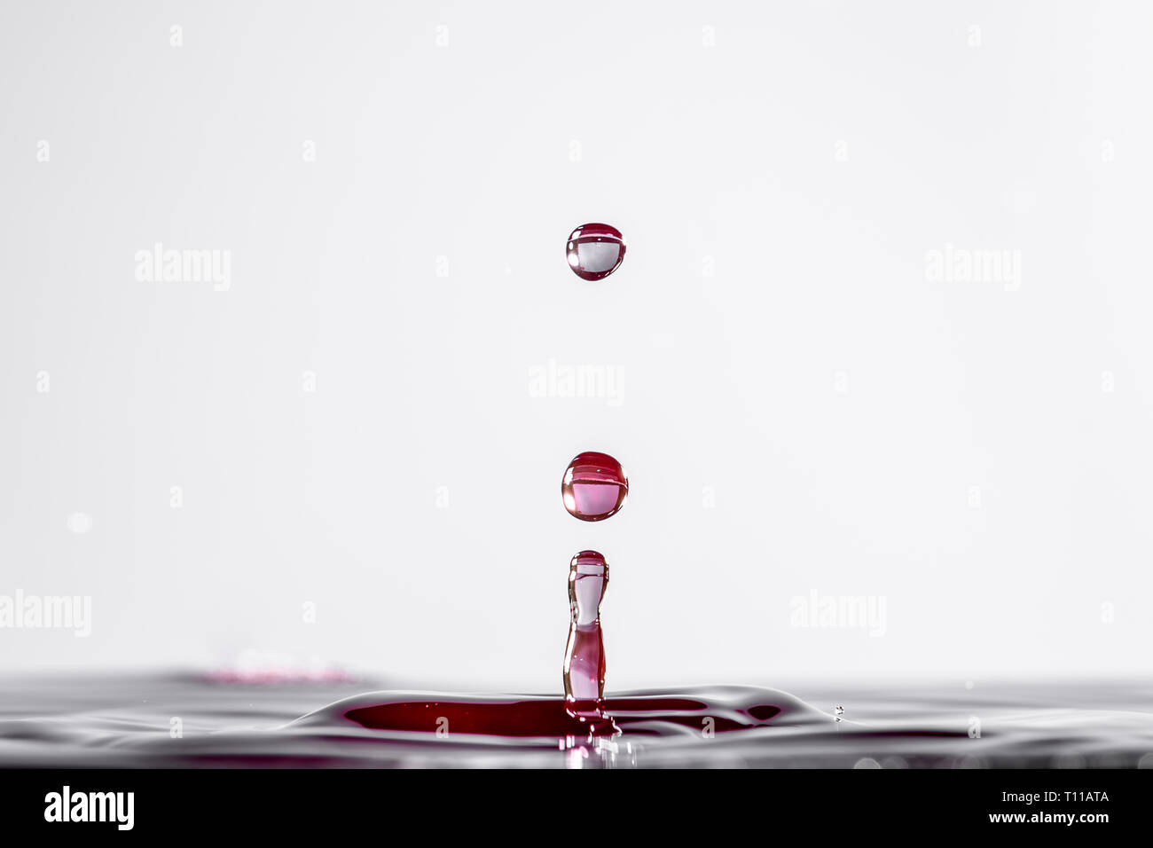 Vibrant red water droplets and ripples isolated on a clean background ...