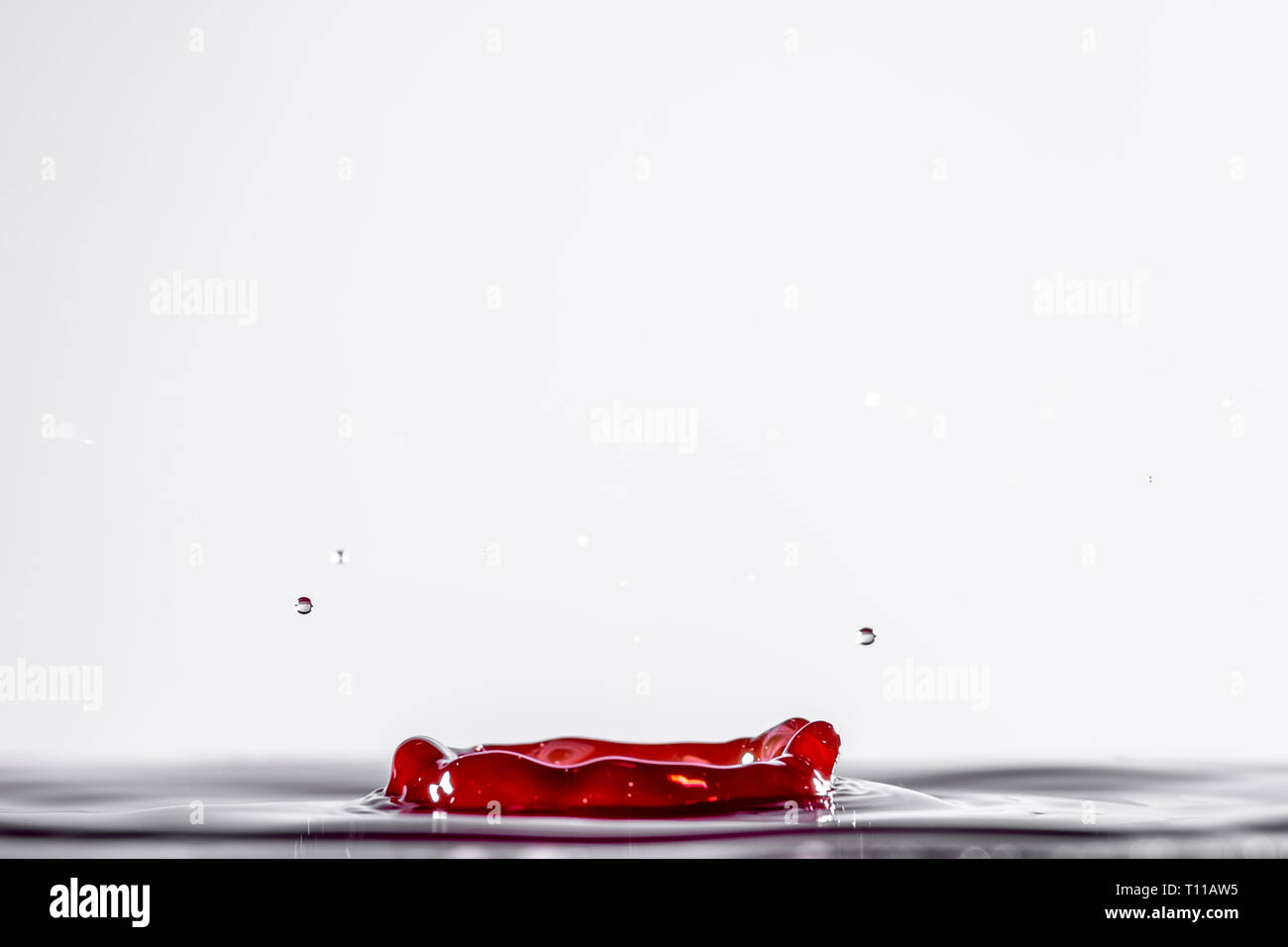 Vibrant red water droplets and ripples isolated on a clean background ...