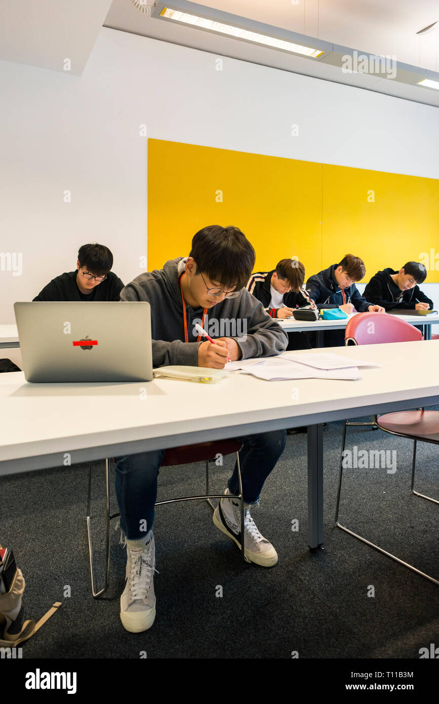 a classroom full of asian international students during a lesson using ...