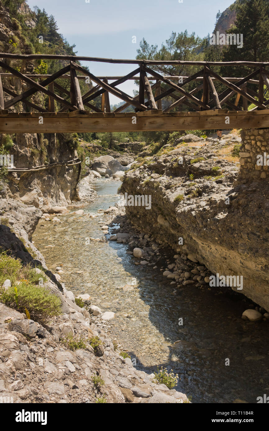 Wooden bridge over mountain river at rocky terrain of Samaria gorge ...