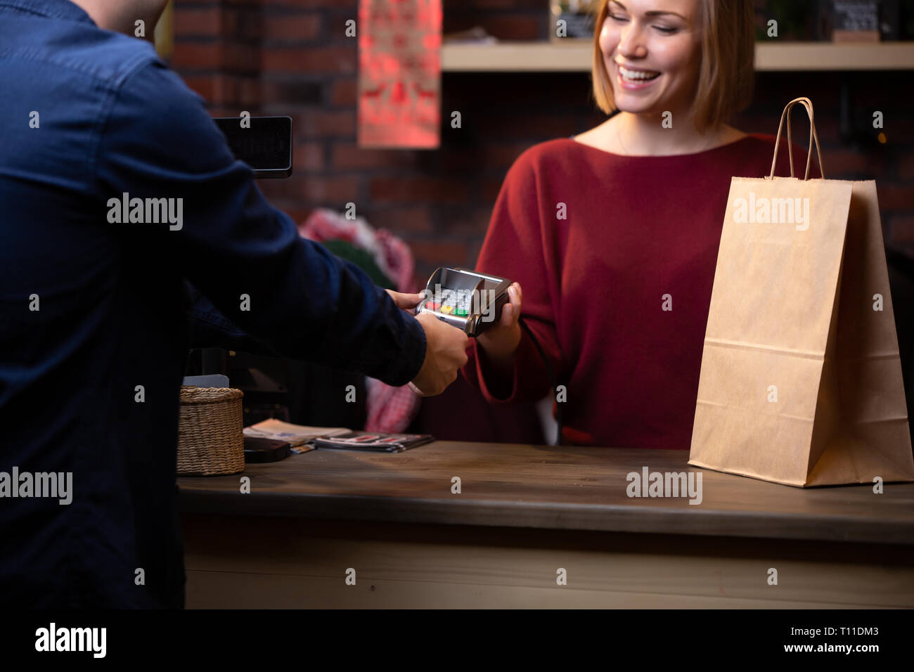 Photo of smiling seller girl standing behind cash register and male ...