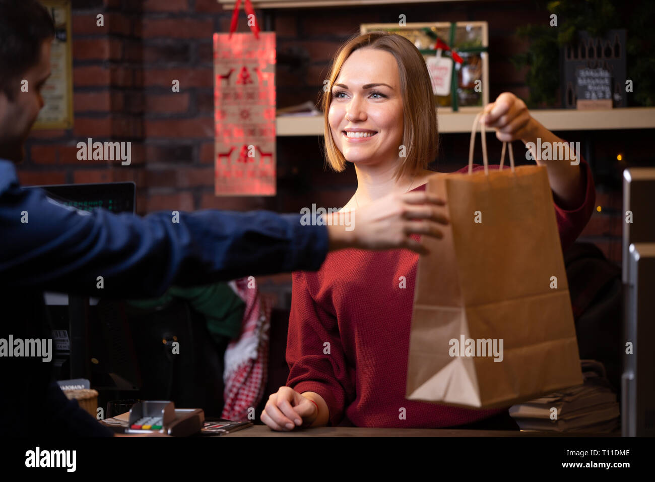 Photo of smiling seller woman giving paper bag to male buyer Stock ... Photo of smiling seller woman giving paper bag to male buyer Stock ...