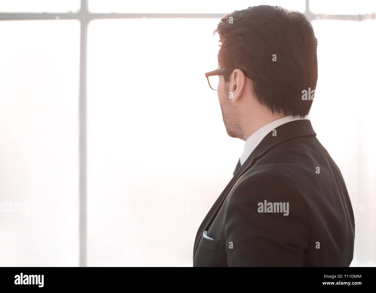side view. businessman standing near the office window Stock Photo - Alamy