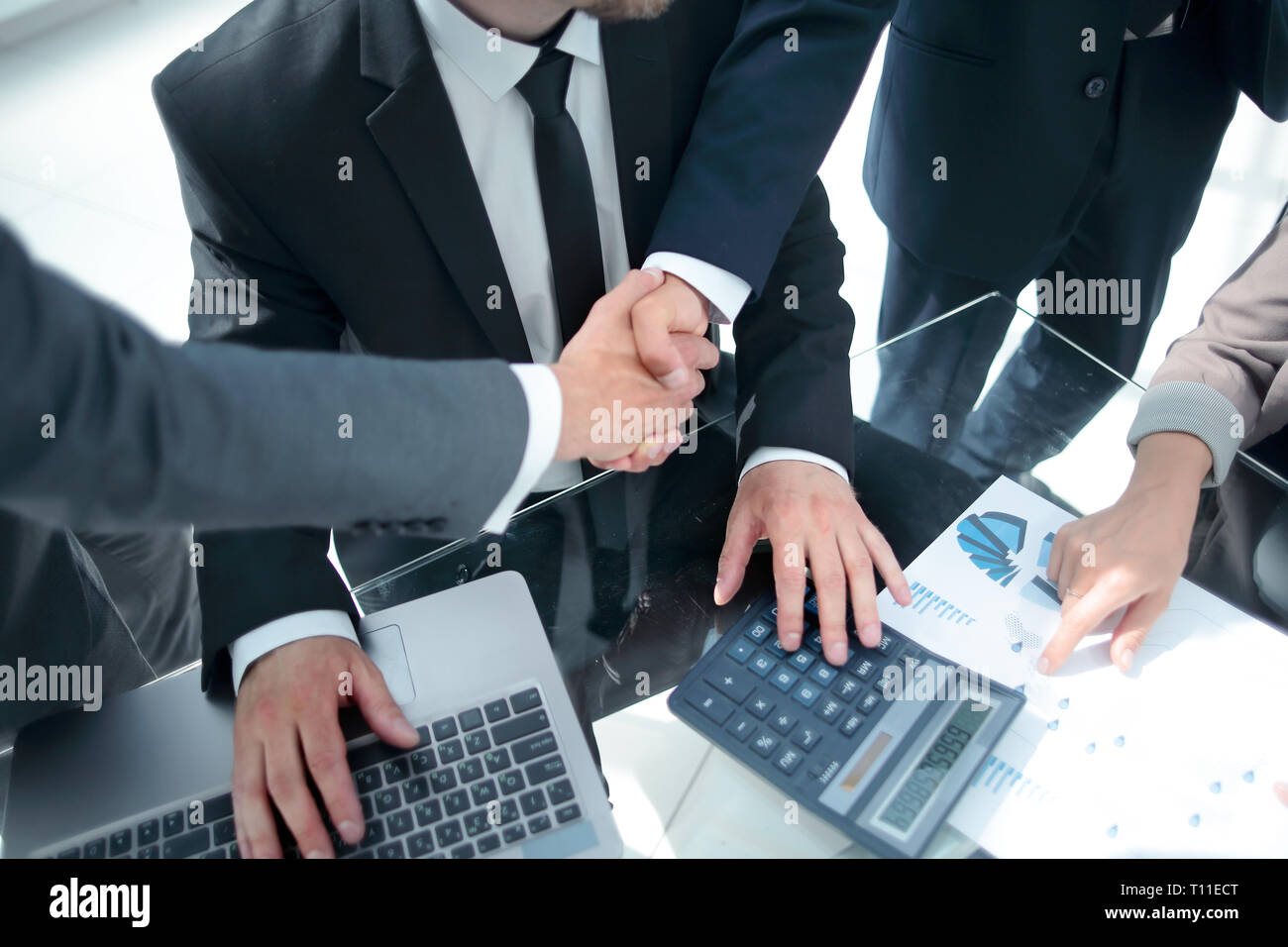 Handshake across the table of financial partners Stock Photo - Alamy