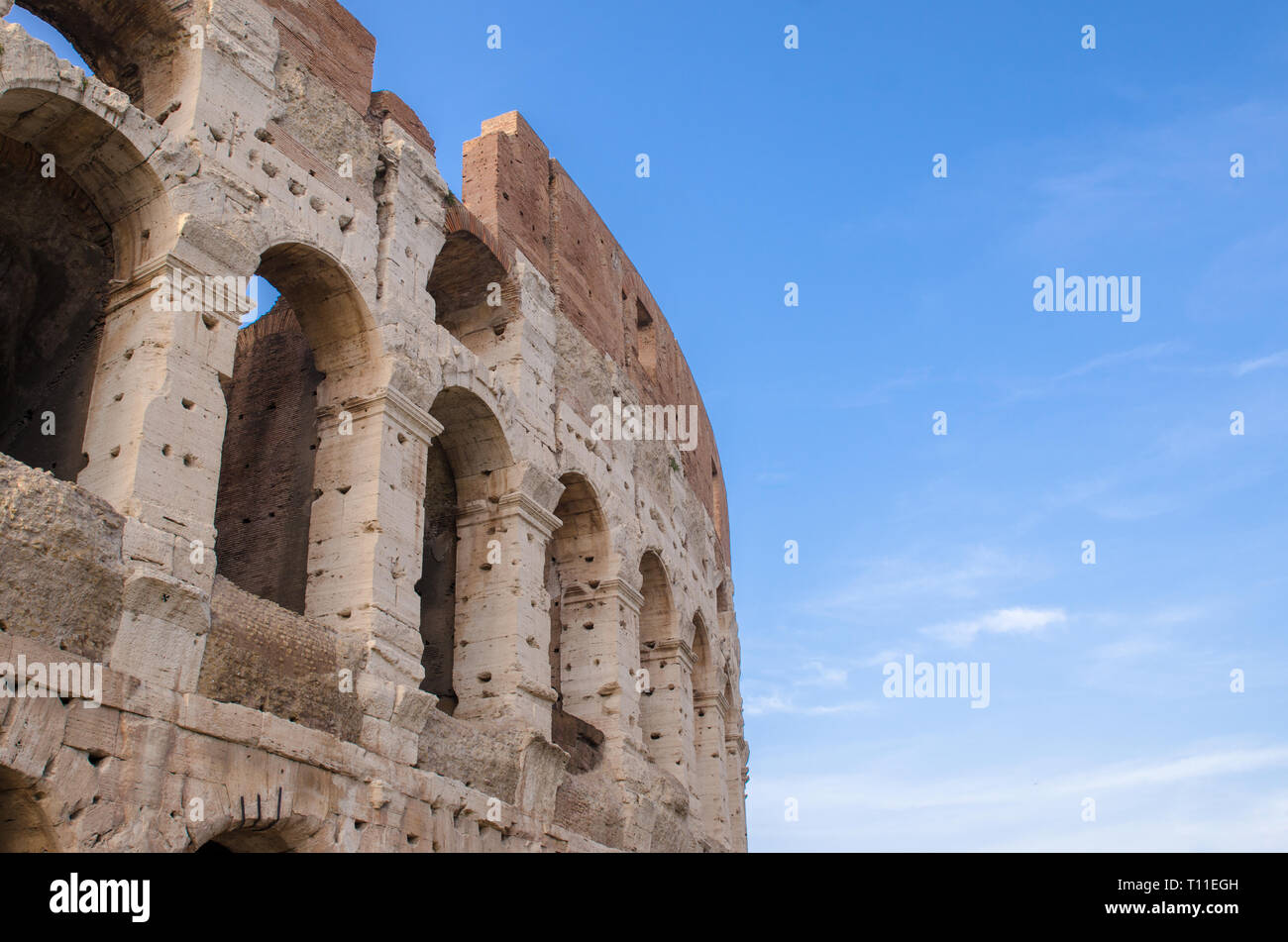 A corner of the top level of the Colosseum in Rome against a blue sky ...