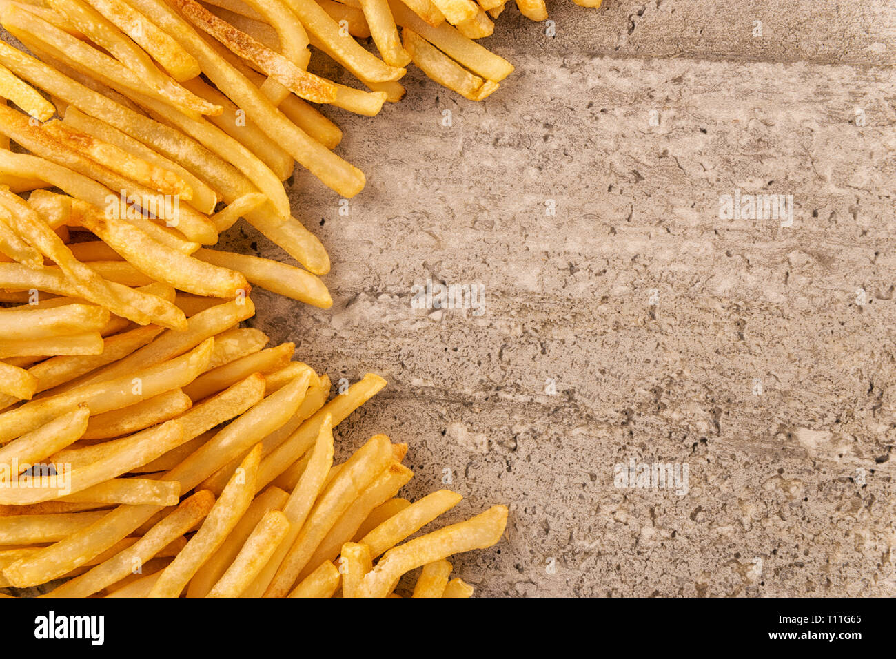 Close up on french fries stack disposed on concrete background ...
