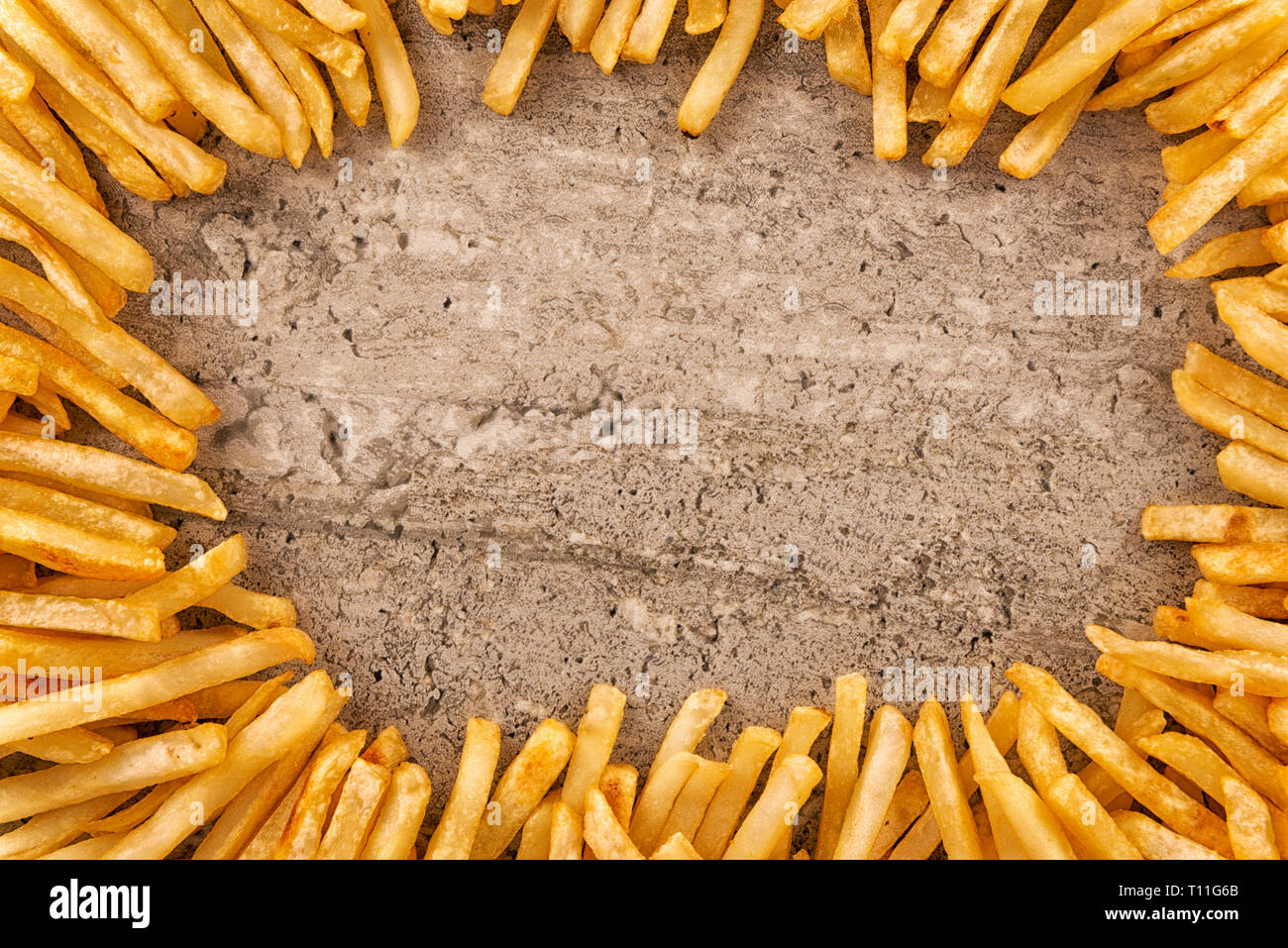 Border of french fries on concrete background, directly above. Close up ...