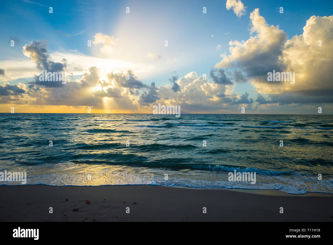 Bright scenic golden sunrise lighting up tropical clouds above gentle ...
