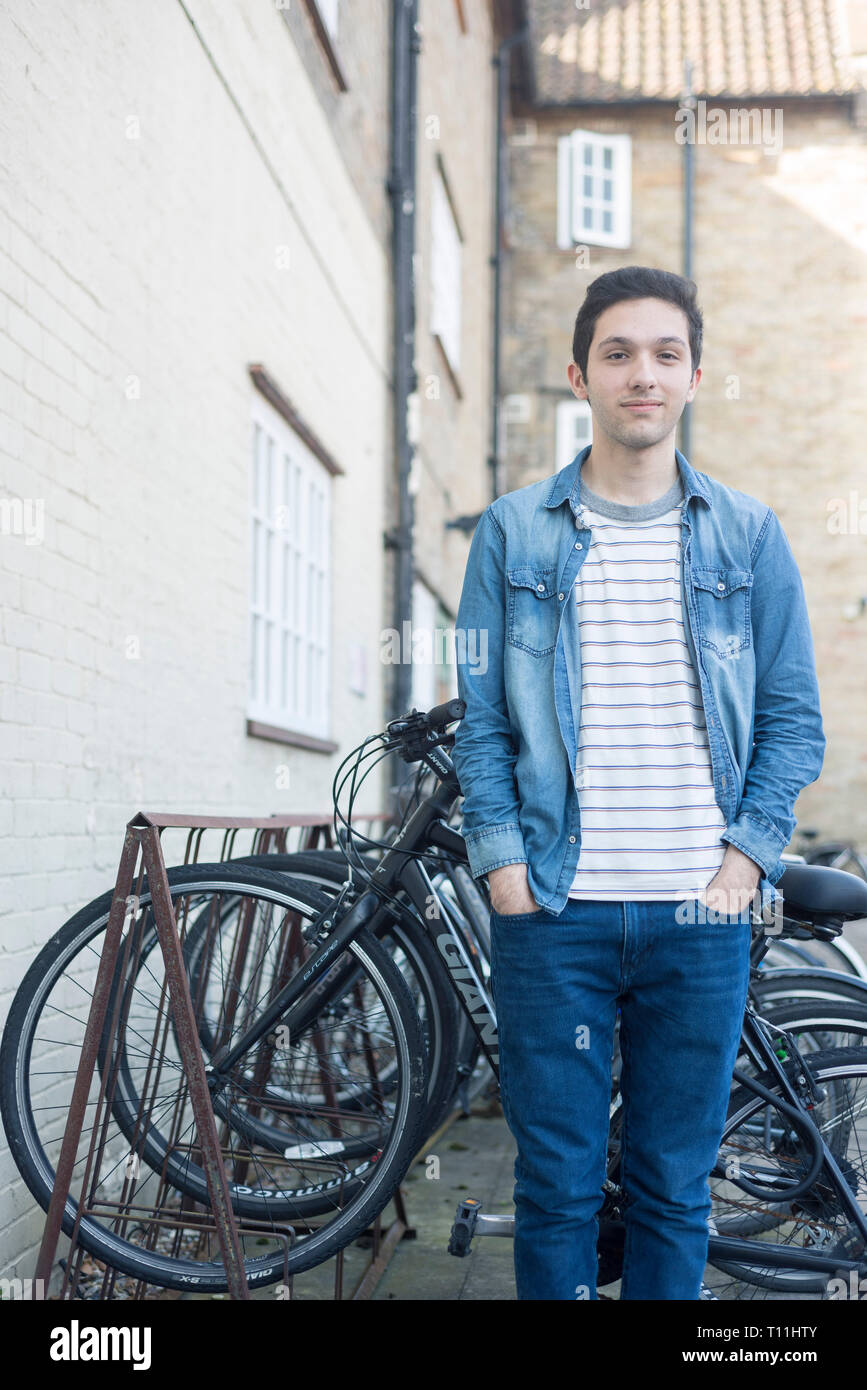 A young man stands amongst a load of bikes in a bike storage location ...