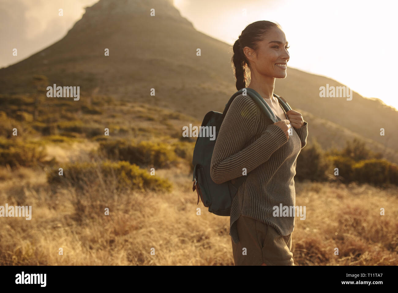 Woman with a backpack on shoulders walking down country road in the ...