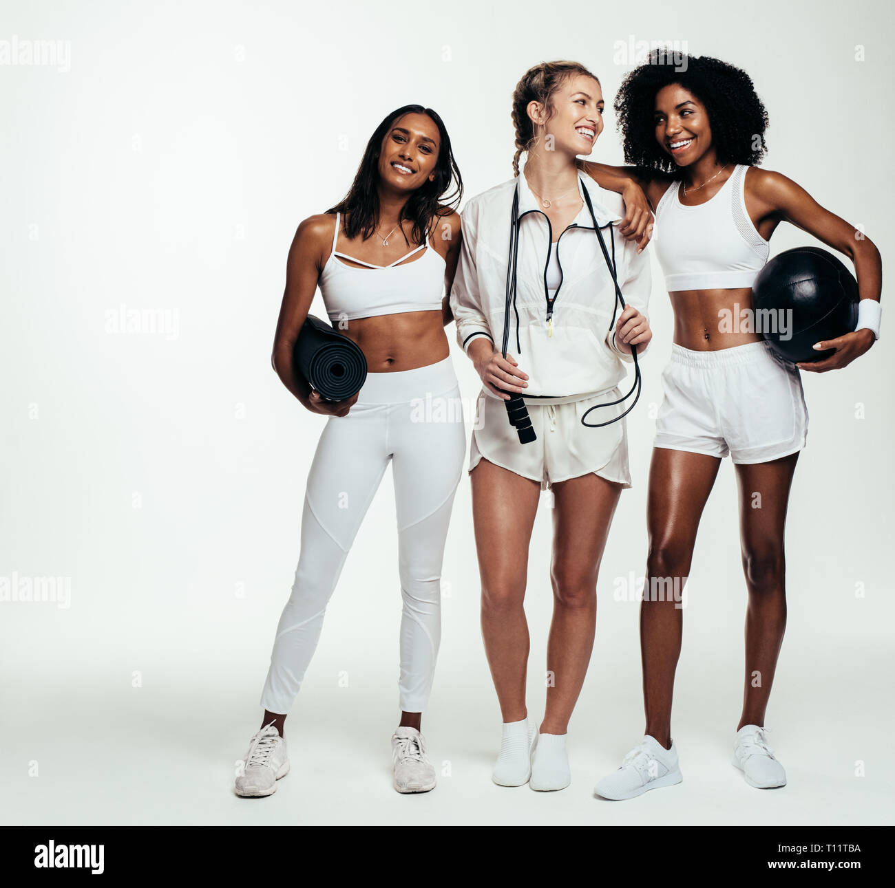 Multi-ethnic group of fitness women together over white background and ...