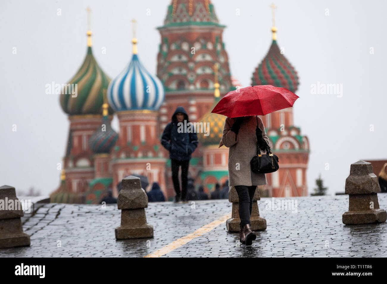 Rainy weather in Moscow. A girl with red umbrella on Red square on the ...