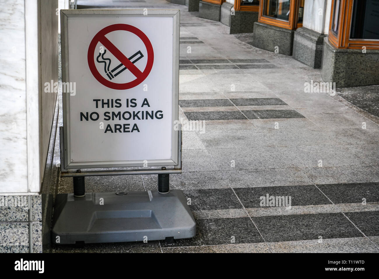 This is a no smoking area sign on posh looking street, marble pavement ...