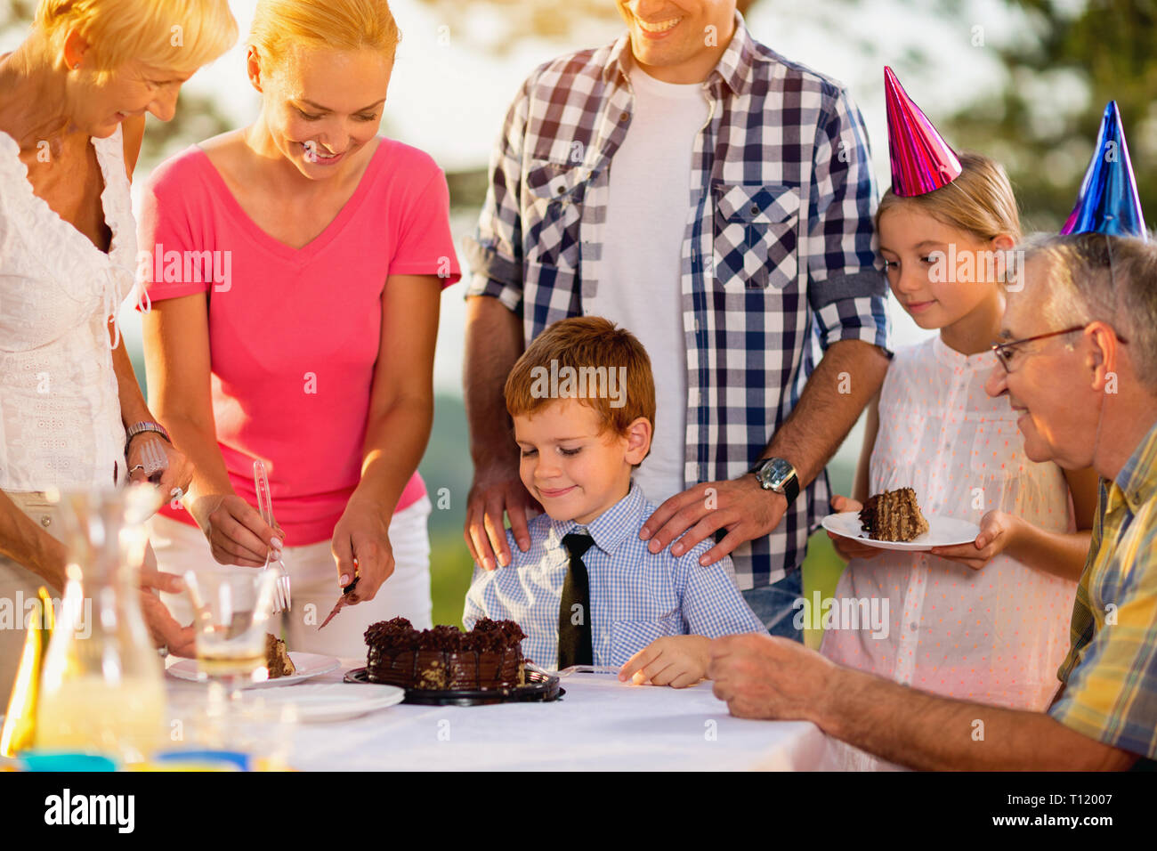boy eating cake at birthday party with family Stock Photo - Alamy