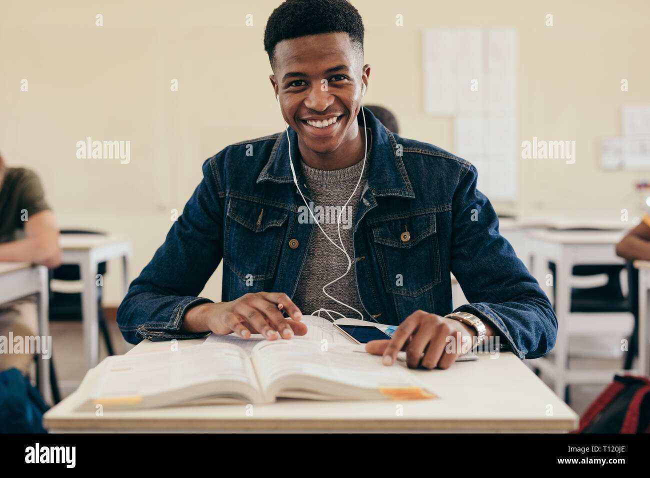 Smiling male student in college classroom with books. Teenage boy ...
