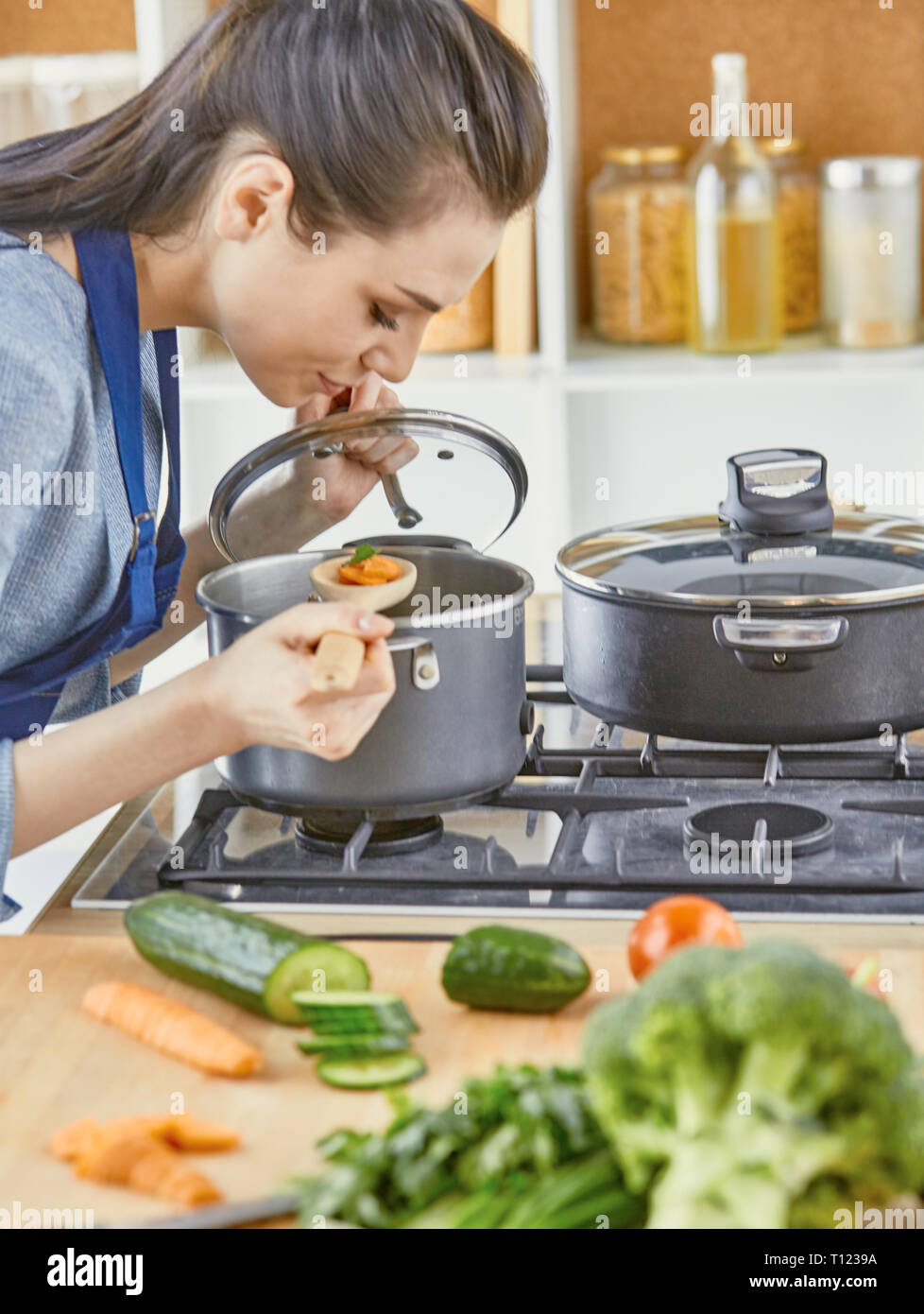 Beautiful girl is tasting food and smiling while cooking in kit Stock ...