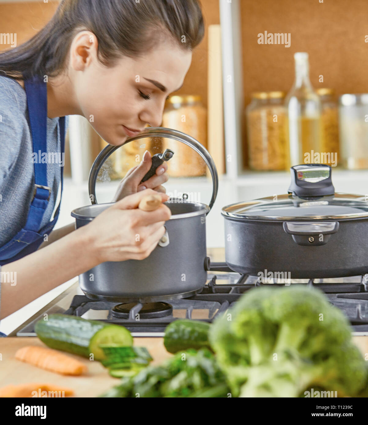 Beautiful girl is tasting food and smiling while cooking in kit Stock ...