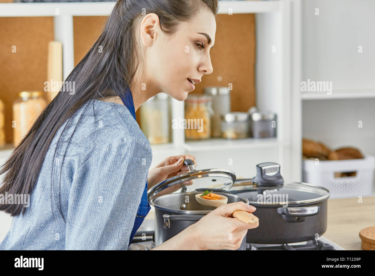 Beautiful girl is tasting food and smiling while cooking in kit Stock ...