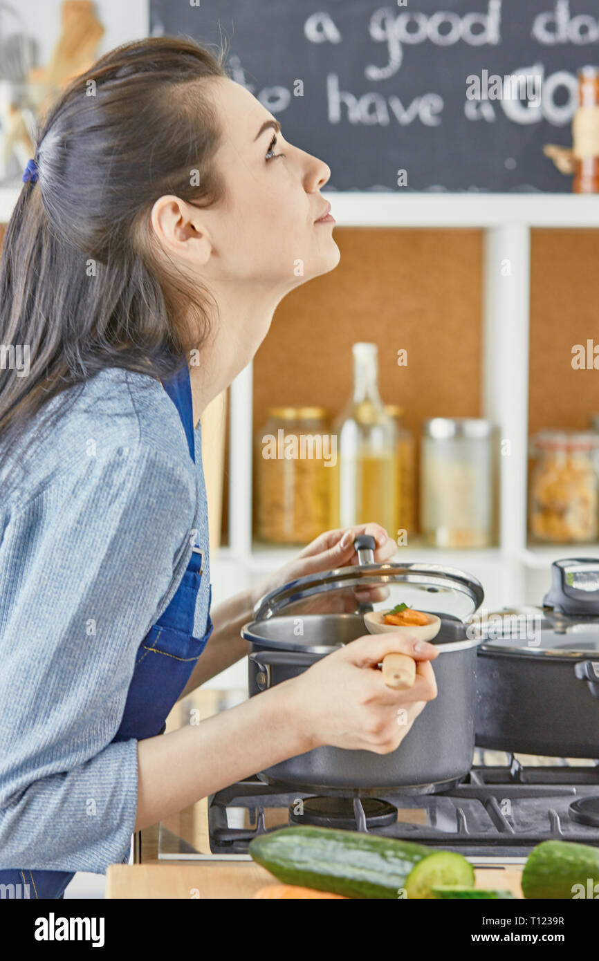 Beautiful girl is tasting food and smiling while cooking in kit Stock ...
