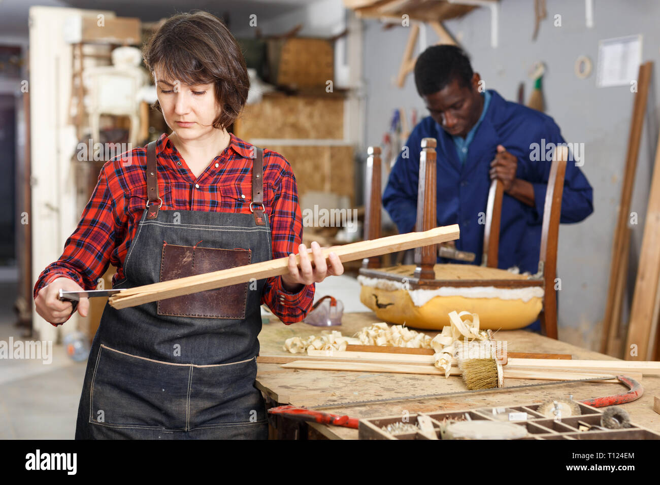 Woman and man carpenters using tools for restoration wooden chair in ...