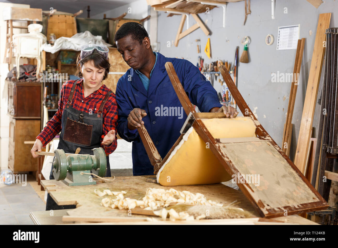 Woman and man carpenters using tools for restoration wooden chair in ...