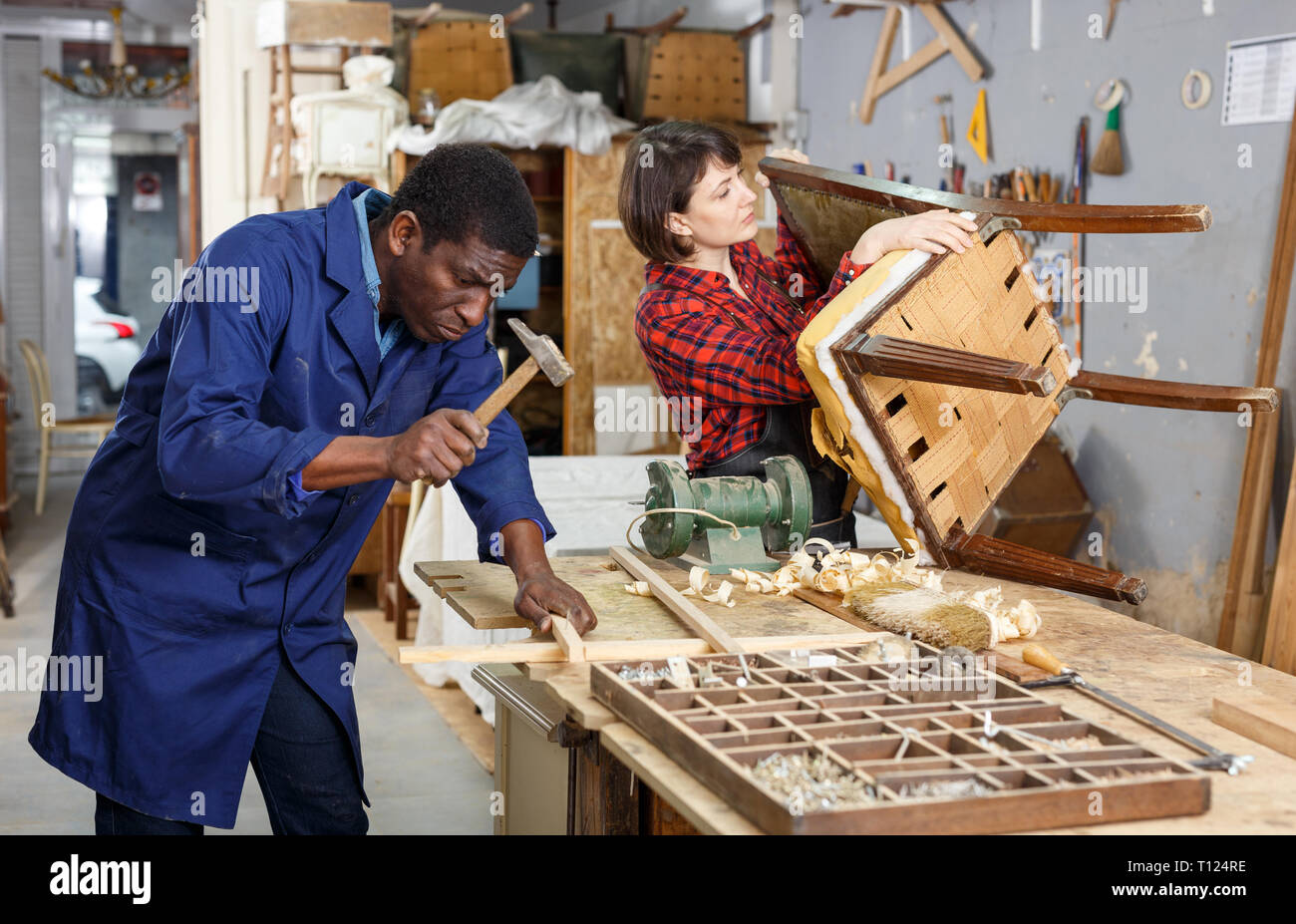 Woman and man carpenters using tools for restoration wooden chair in ...