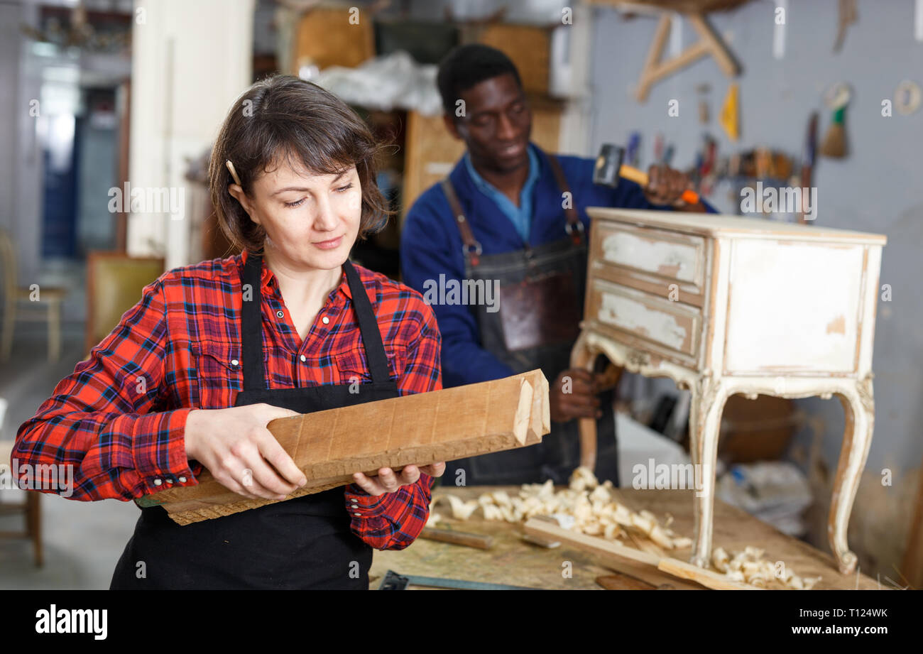 Woman and man carpenters using tools for restoration wooden bureau in ...