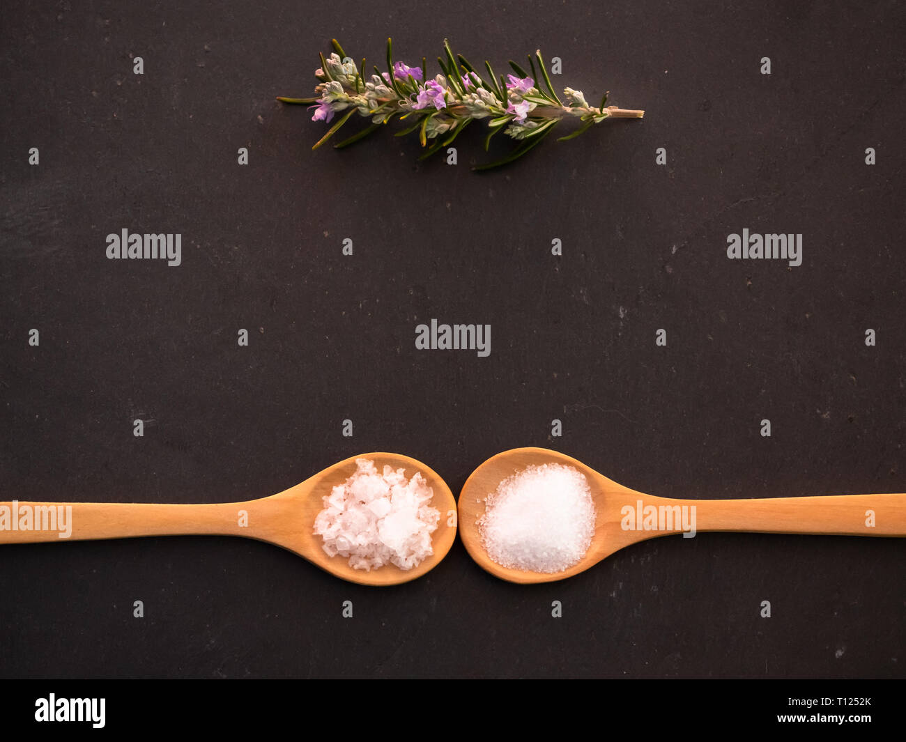 Wooden spoons with common marine salt and salt flower flakes on a slate ...