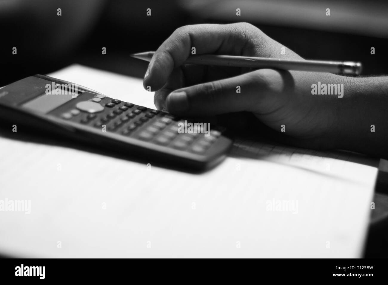 Student working on his homework with a calculator in a dimly lit ...