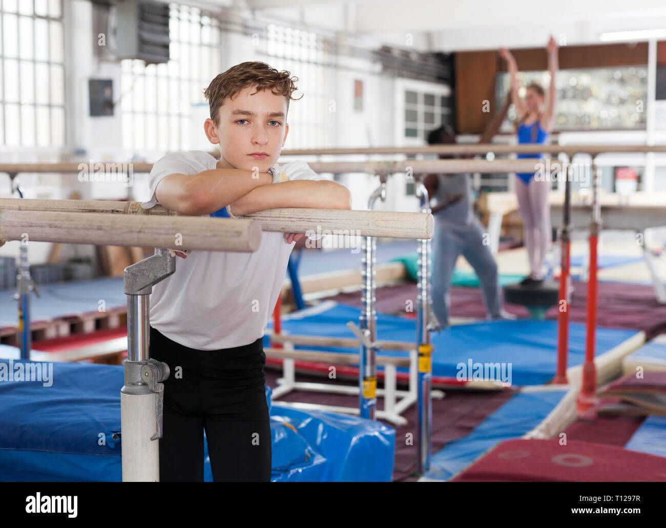 Portrait of sad teenage athlete standing near gymnastic equipment at ...