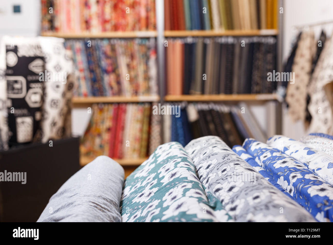 Variety of different fabric bolts exposed on shelves of fabric shop ...