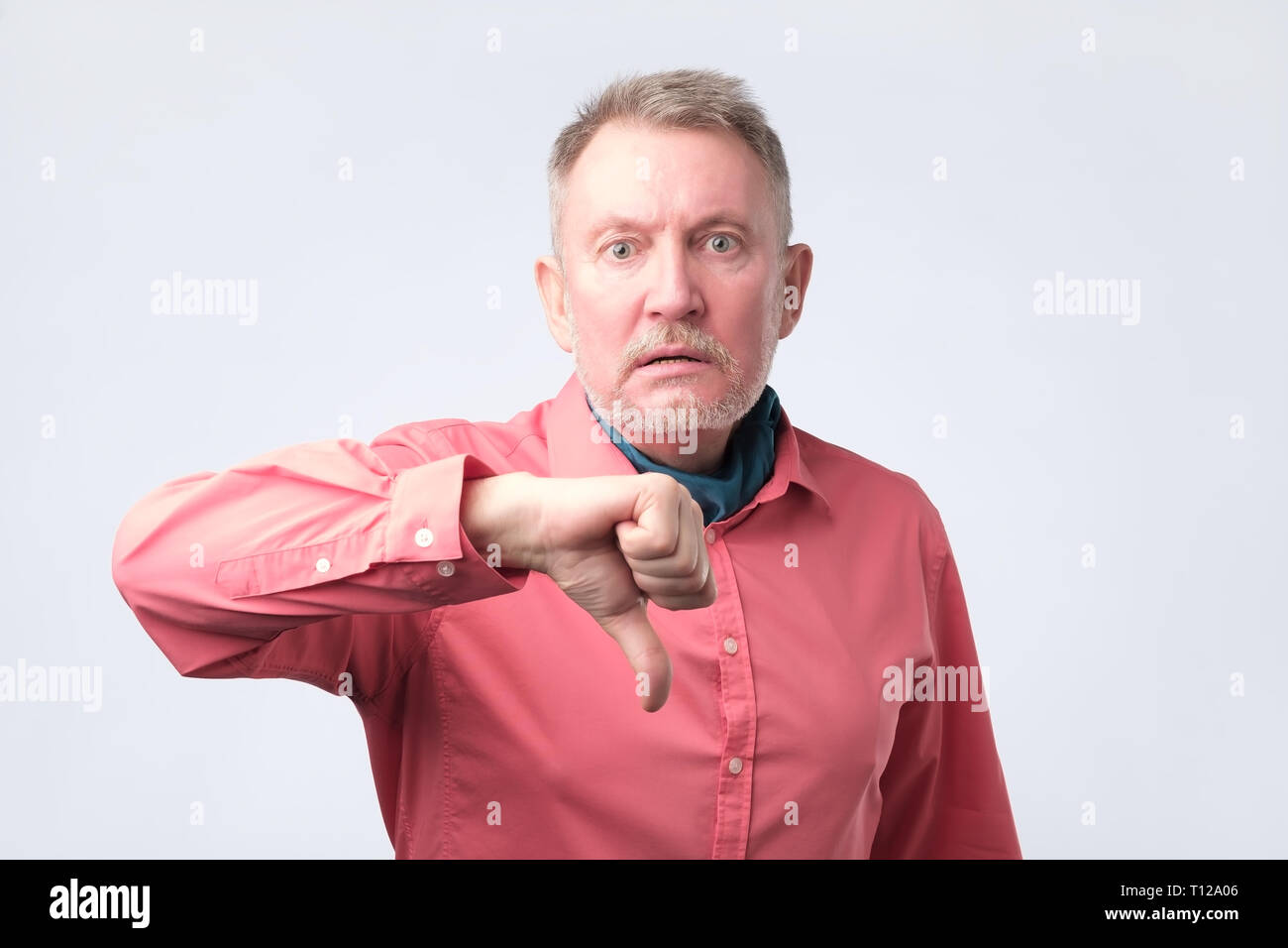 Senior handsome man in red shirt showing thumbs down gesture. Negative ...