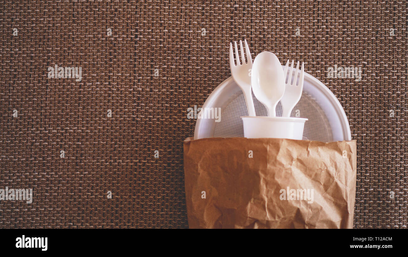 White plastic dishes in a paper packet on beige background. Concept of ...