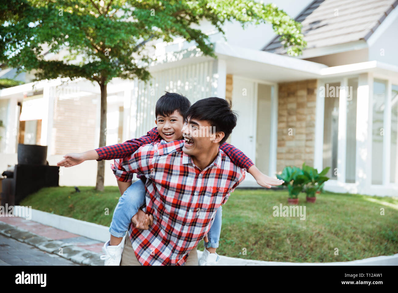 father piggyback ride with his son in front of the house Stock Photo ...