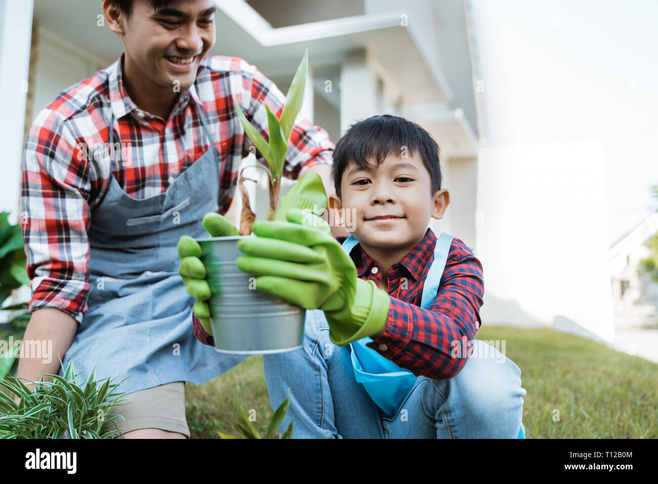 dad and son planting a plant gardening at their house together Stock ...