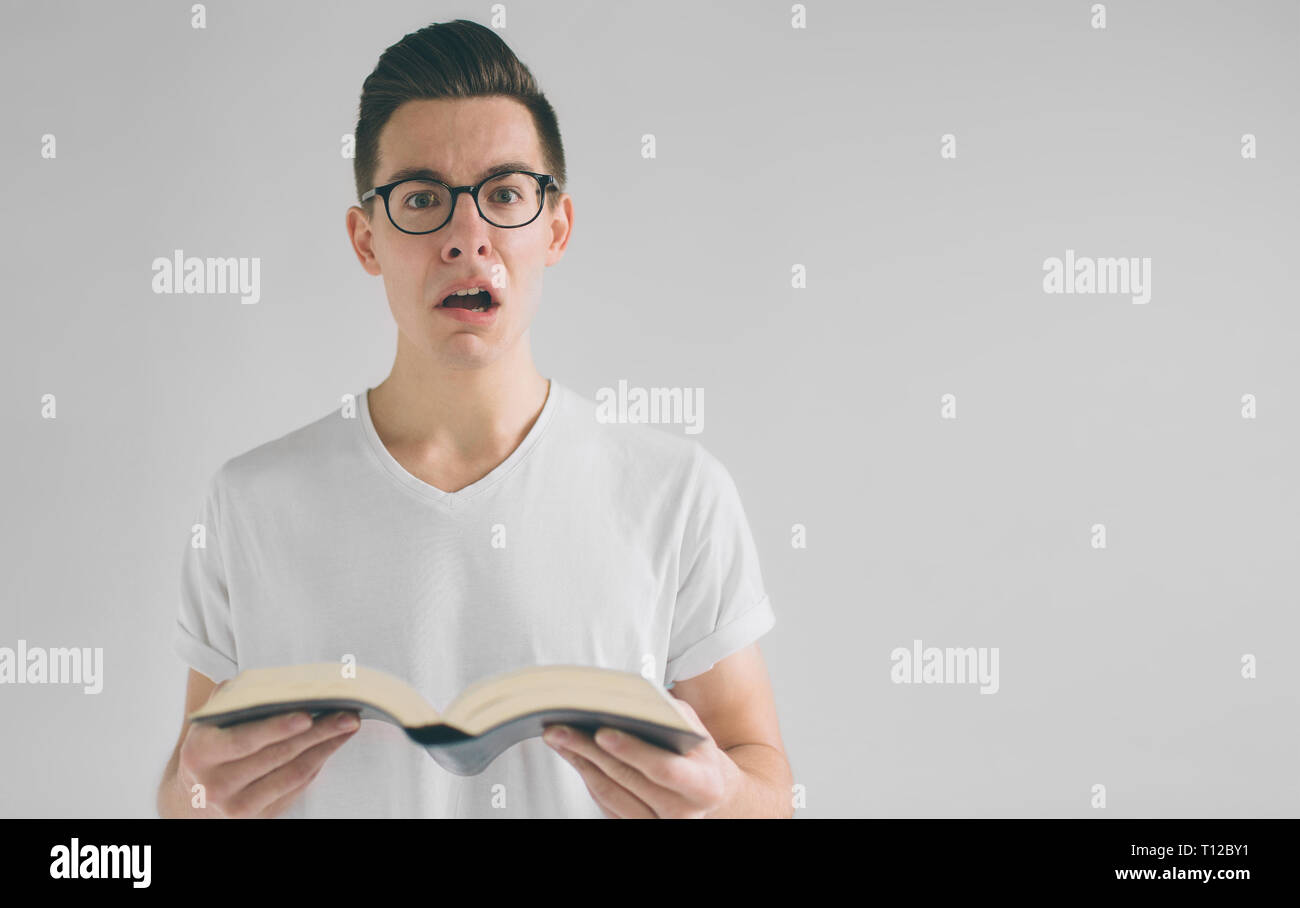 nerd with glasses and a white t-shirt is reading a book on a white ...
