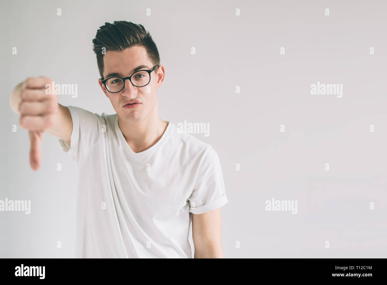 Nerd is wearing glasses. casual young man showing thumbs down sign ...