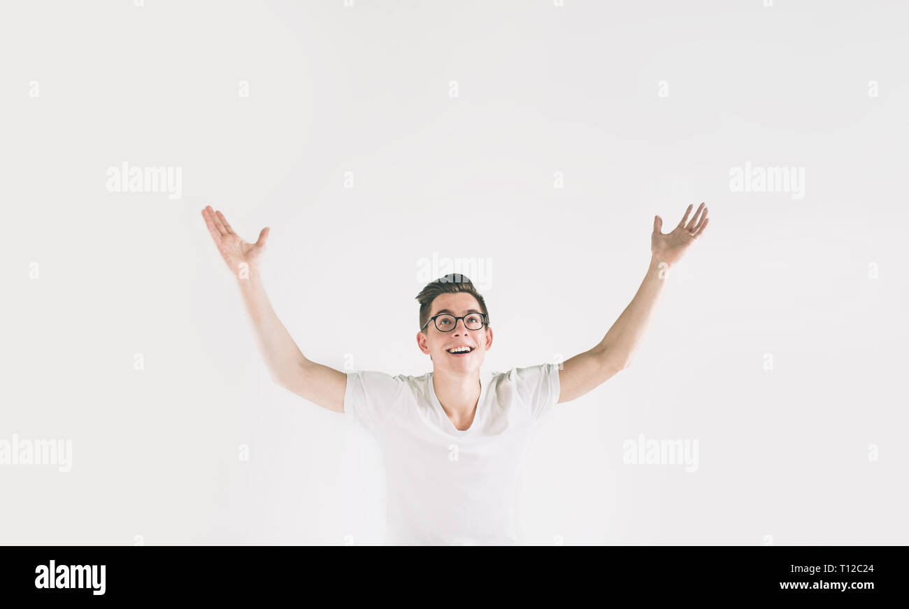 Young happy man with in casuals with raised hands up isolated on white ...