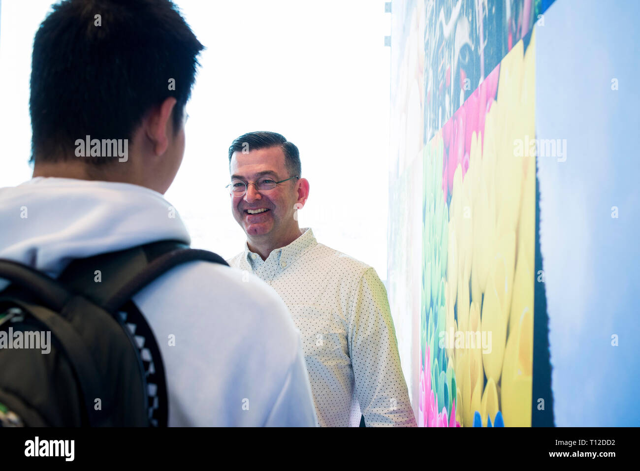 A student and teacher chat against a bright modern wall Stock Photo - Alamy