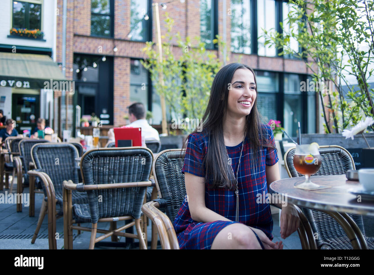Two young international students sit outside a coffee shop / bar ...