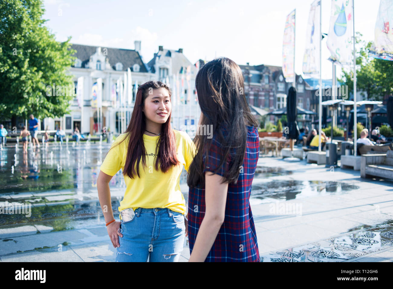 Two students stand in Tilburg square in the town centre talking and ...