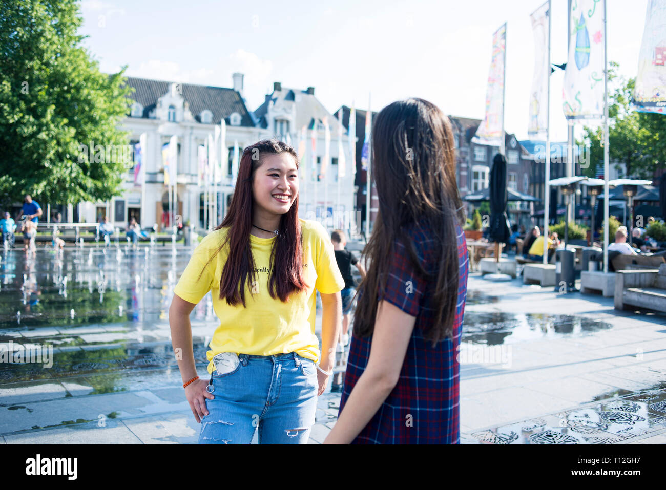 Two students stand in Tilburg square in the town centre talking and ...