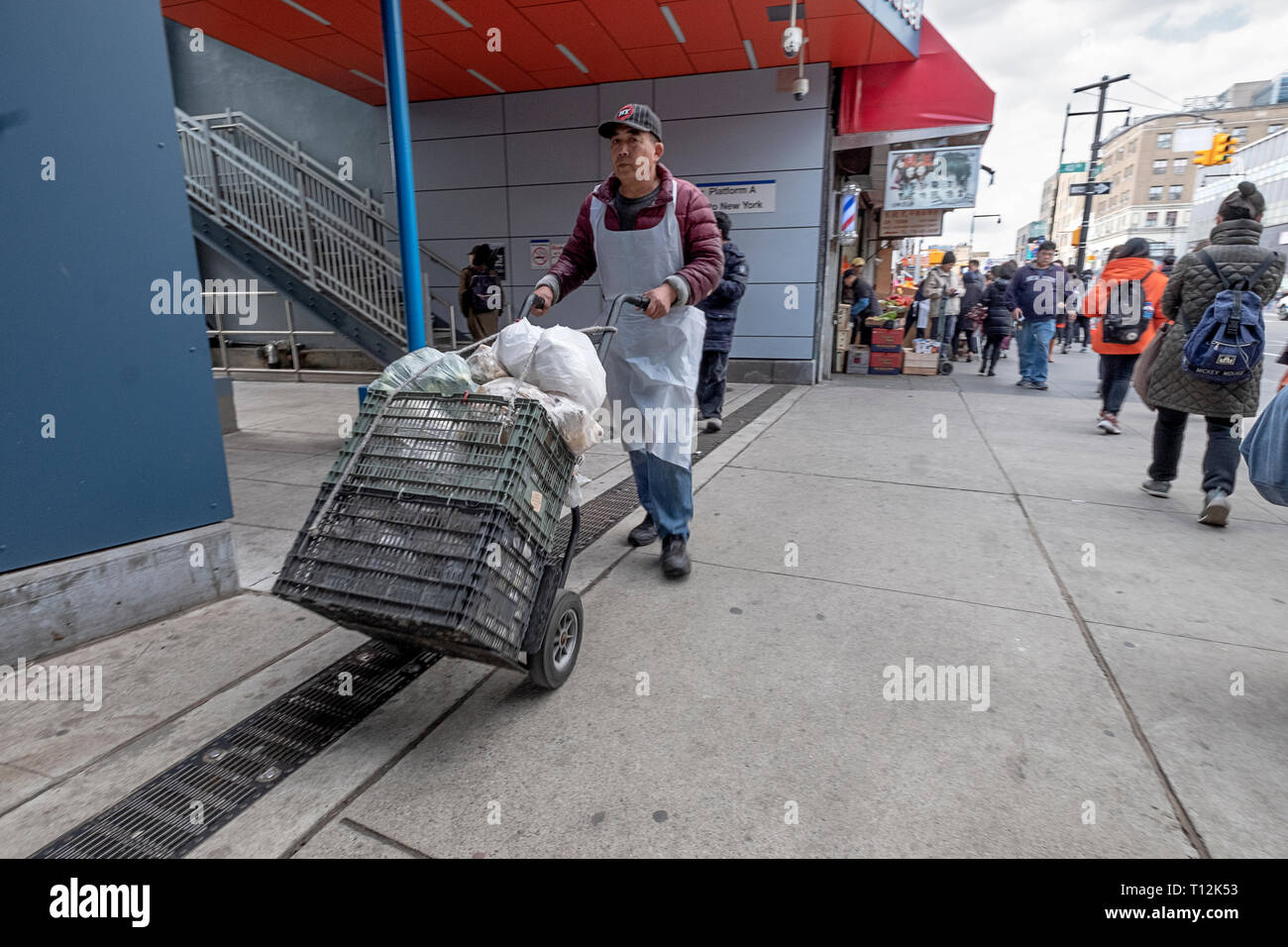 A Chinese worker in an apron transporting bags of food on Main St. In ...